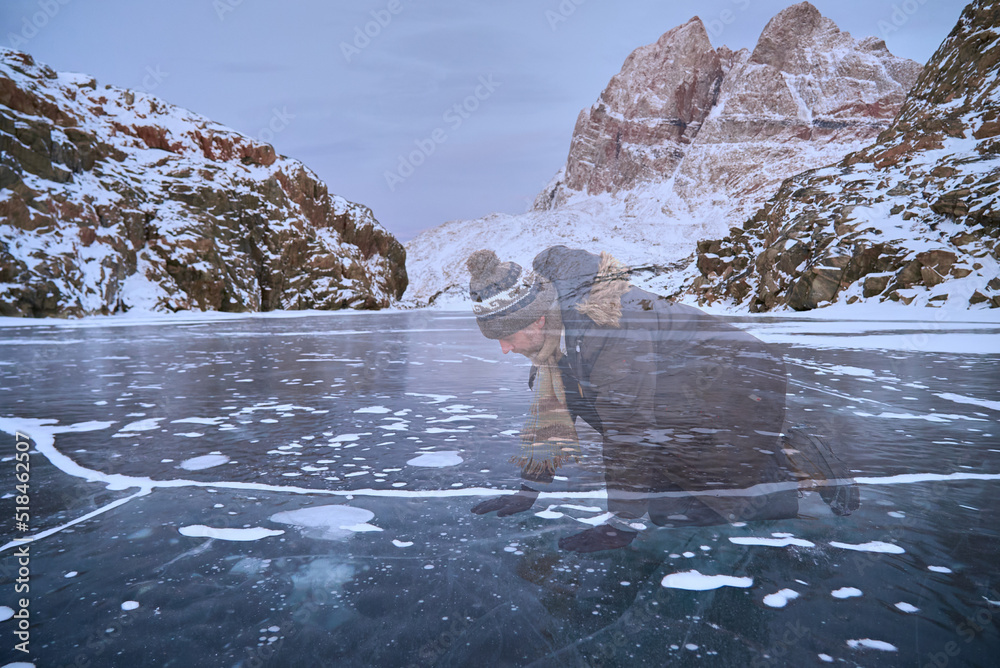 Arctic winter, person half dissolved atop frozen sea ice surface crack ...