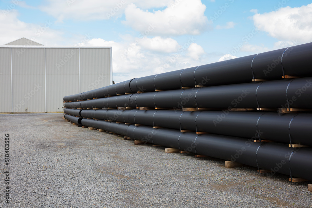 Stacks of polymer pipes and tubes outside of manufacturing facility ...