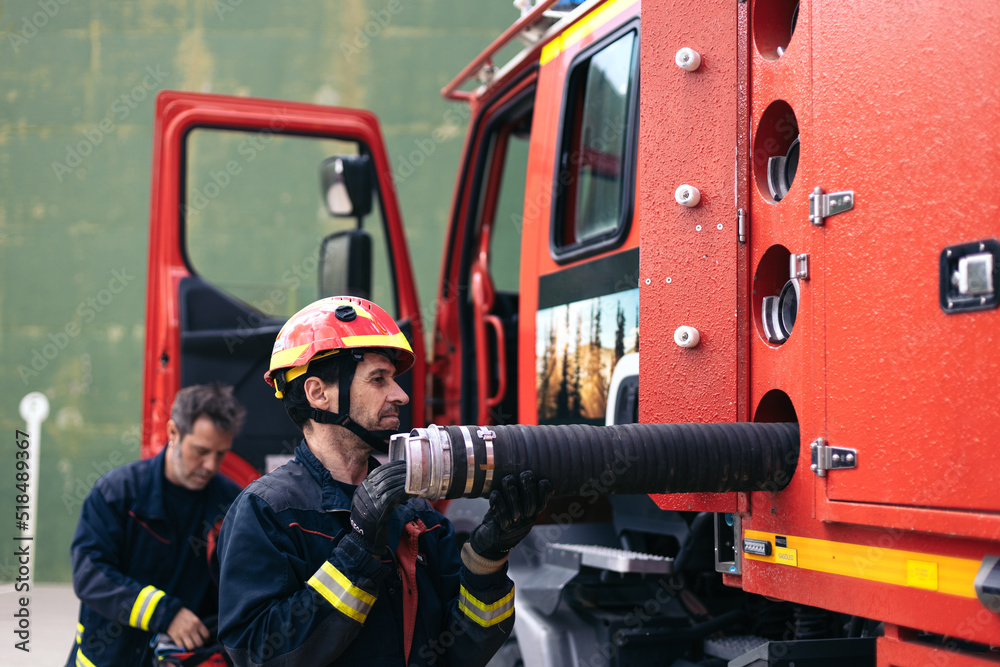 Firefighters at work pulling the hose out of the fire truck Stock Photo ...