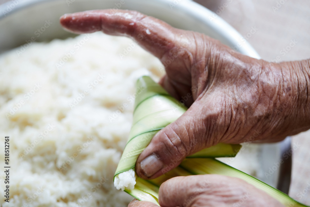 Hands of a senior woman wrapping the sticky rice with palm leaf or ...