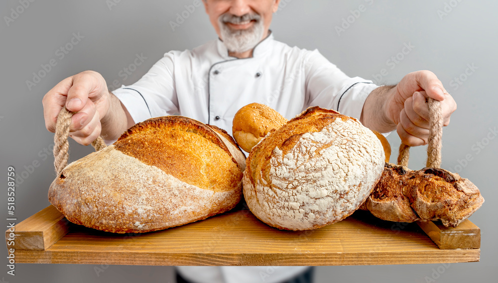 Chef-cooker in a chef's hat and jacket working in bakery, holding tray ...