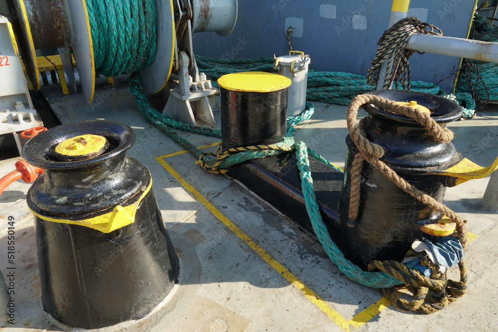 Close view on black and yellow painted bollards and mooring roller in ...