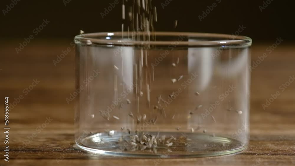 Condiment falling into transparent jar in wooden table background ...