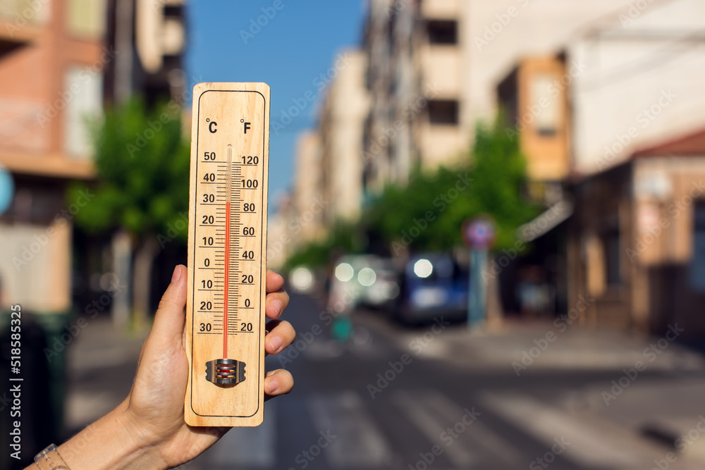 Hot weather. Thermometer in front of an urban scene during heatwave ...