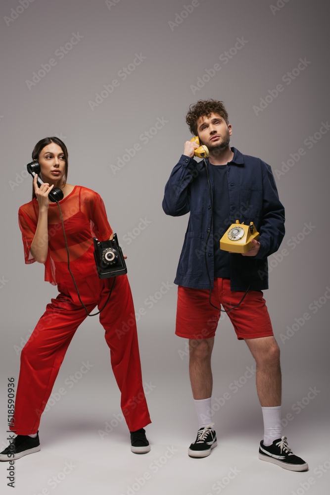 full length of young models holding handsets and retro telephones on ...