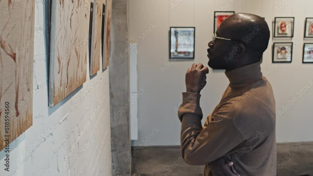 Waist-up side view of young intelligent Black man observing series of ...
