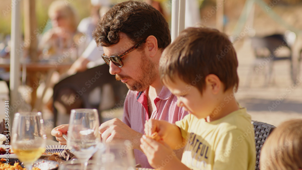 Family and friends gathered for lunch enjoying a delicious paella in a ...