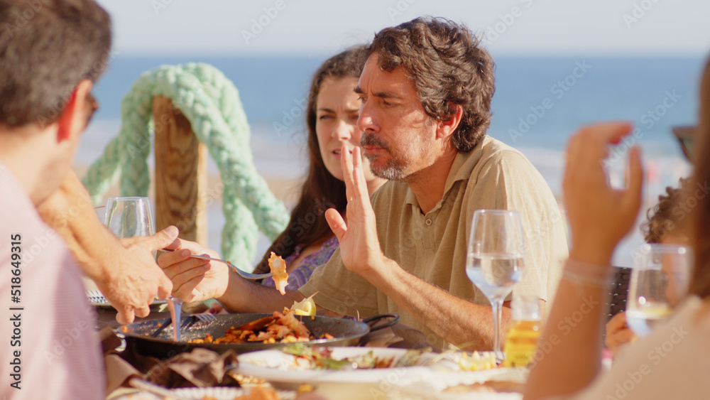 Family and friends gathered for lunch enjoying a delicious paella in a ...