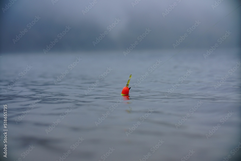 Orange and green fishing bobber floating in the water Stock Photo ...