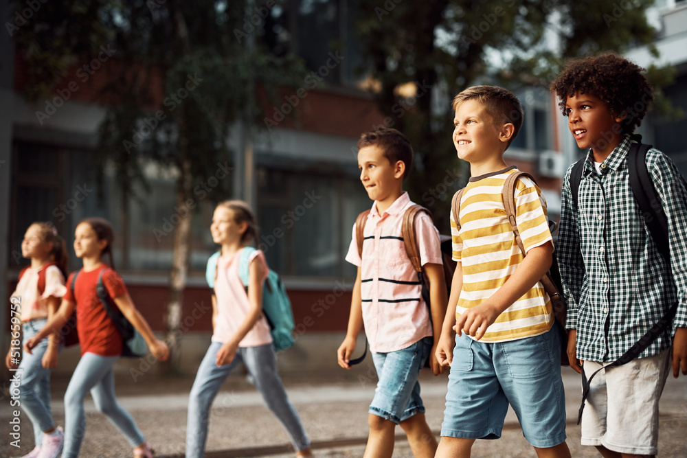 Multiracial group of happy elementary students going to class at school ...