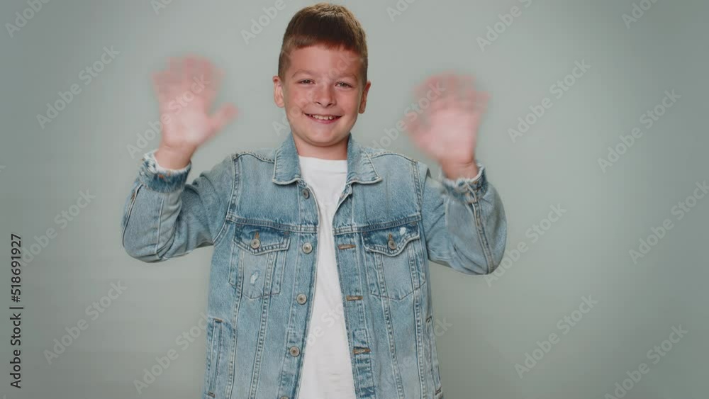 Beautiful toddler boy smiling friendly at camera and waving hands ...