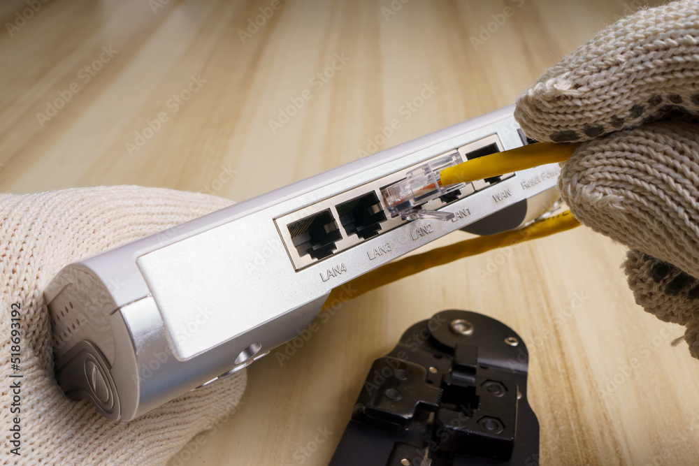 Gloved hand connecting a network cable to one of the output ports of a ...