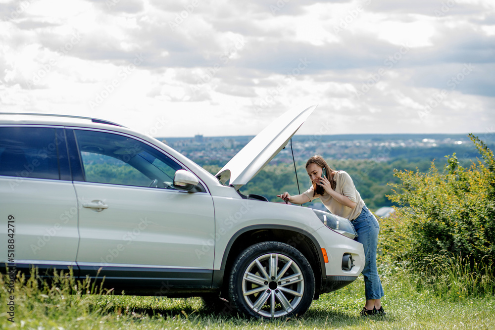 The woman pulls out a probe in her car engine to check the oil level ...
