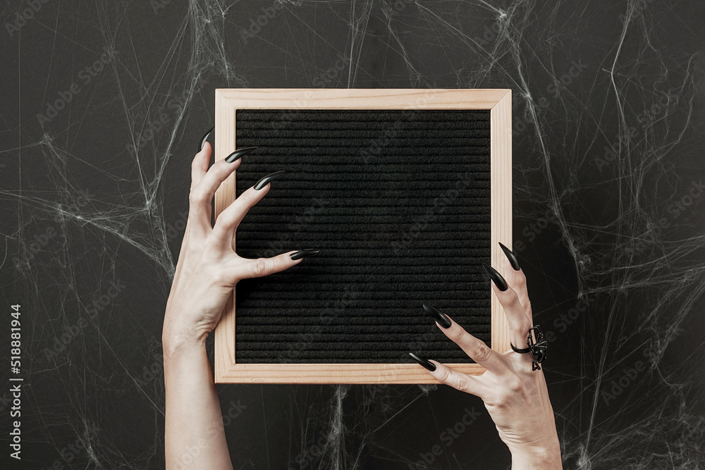 Halloween mock up. Letter board in hands with long black nails and ...