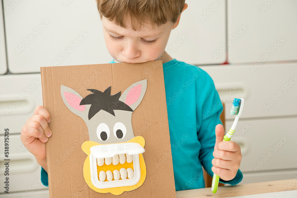 A dentist. Kid plays with DIY toy. Boy washing donkey teeth with ...