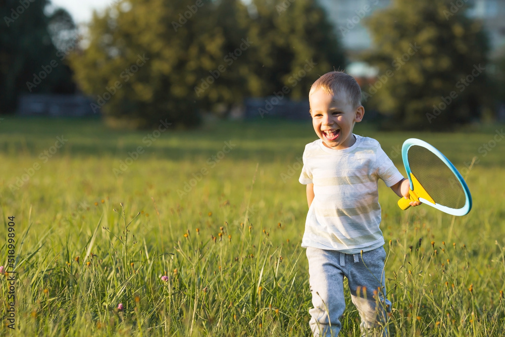 Running smiling little boy with a racket in his hands. Playing ...