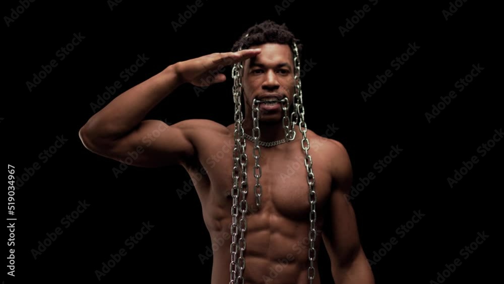 Vidéo Stock Muscular man showing muscles and biting a metal chain ...