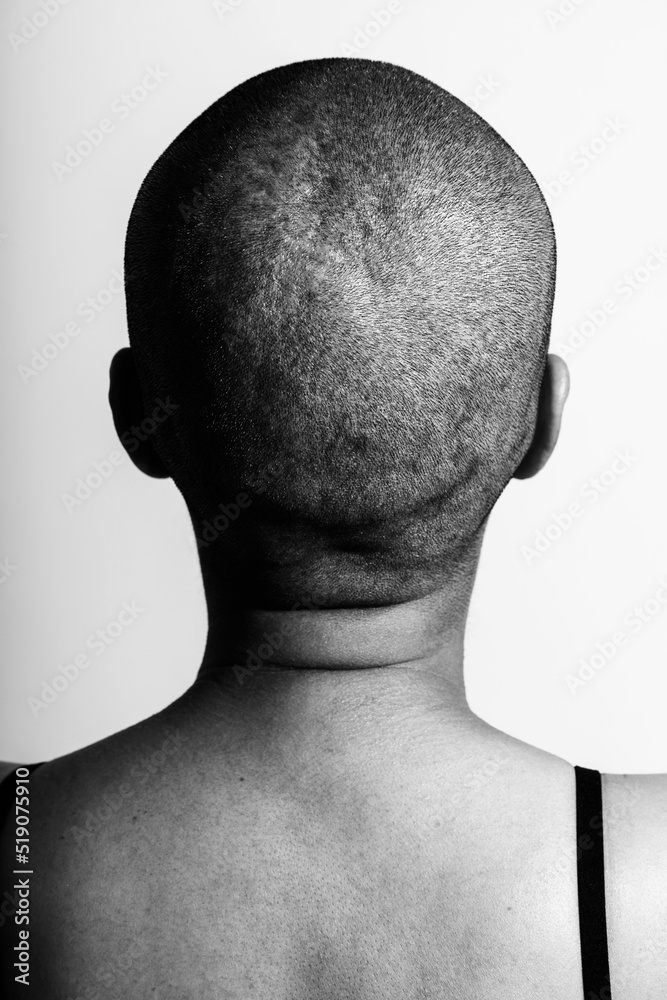 Abstract portrait. Woman standing back to camera with shaved head in ...