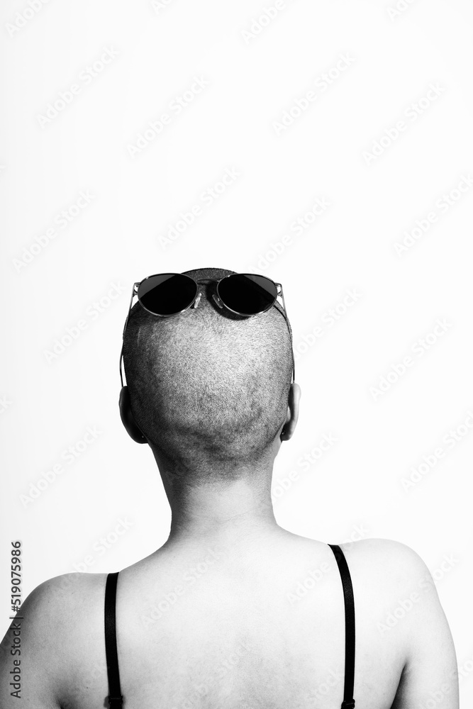 Woman standing back to camera with shaved head and sunglasses on it in ...