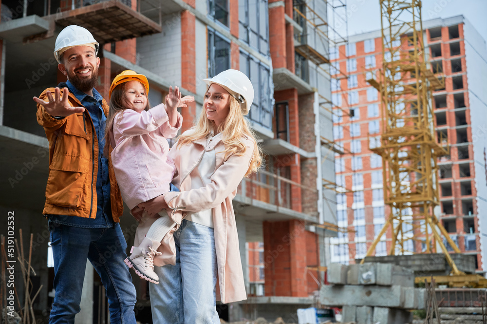 Man, woman and child standing outside building under construction ...