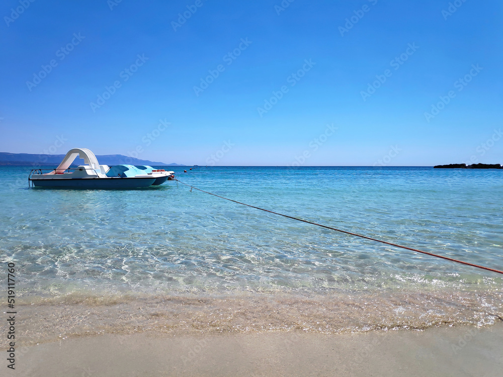 Spiaggia in riva al mare con acqua limpida e pedalò Stock Photo | Adobe ...