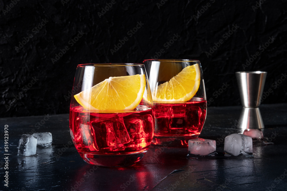 Campari aperitif with fresh orange slices and a jigger, on a black ...