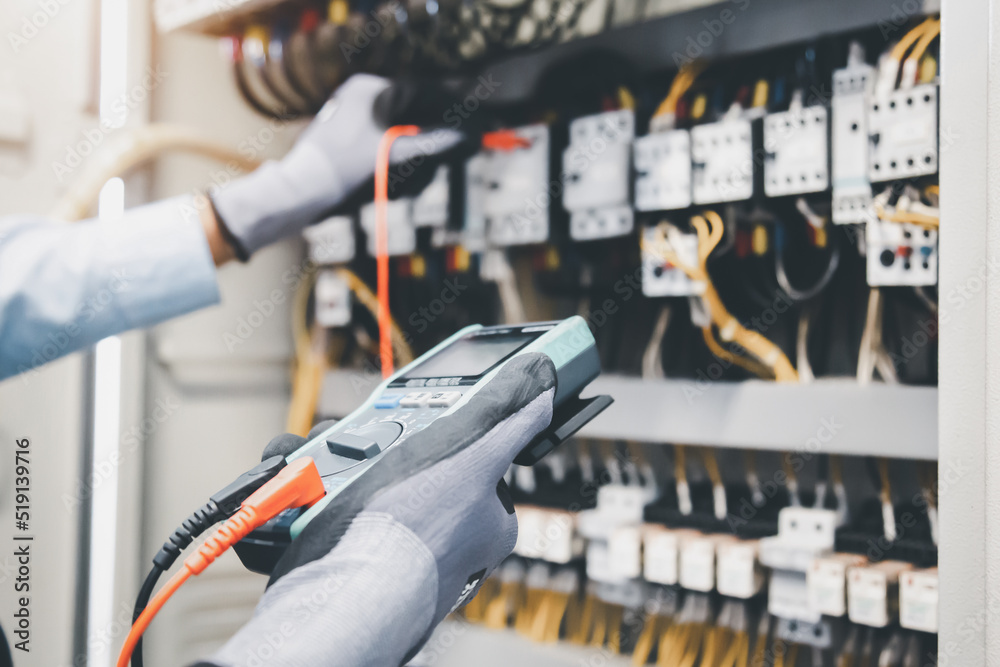 Electrical engineer using digital multi-meter measuring equipment to ...