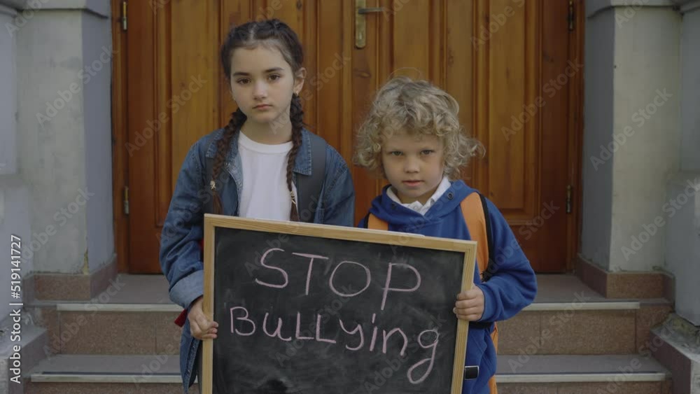 Sad boy and girl looking at camera and holding chalkboard with ...