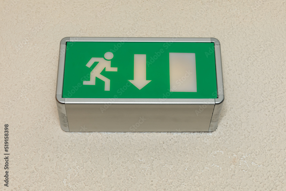 Emergency Exit sign in a hospital. Illuminated green exit sign on the ...