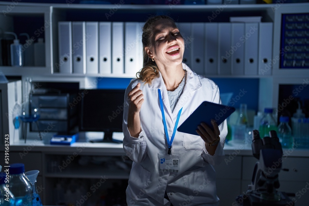 Beautiful blonde woman working at scientist laboratory late at night ...