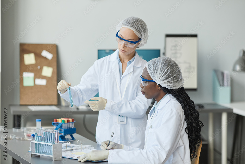 Portrait of two young women holding test tubes in laboratory while ...