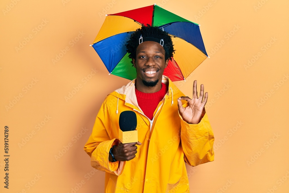 Young african american journalist man wearing yellow raincoat and ...