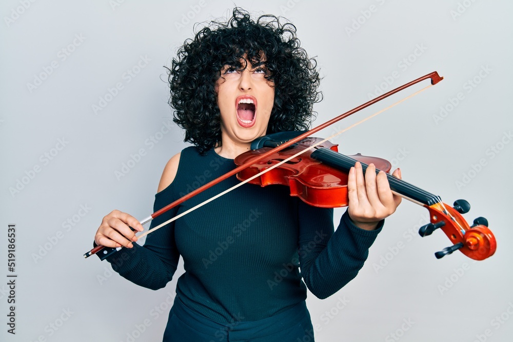 Young middle east woman playing violin angry and mad screaming ...