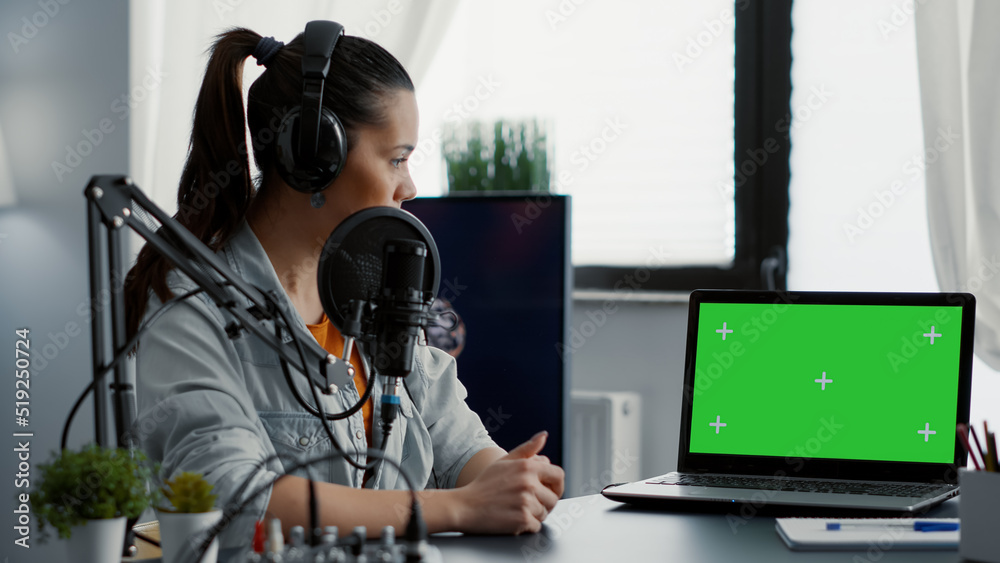 Influencer in studio presenting product on laptop with green screen ...