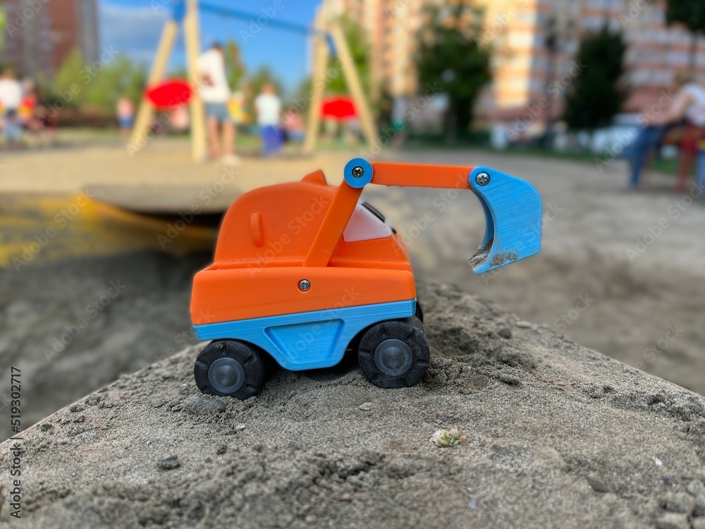Vivid colorful orange toy excavator with big black wheels and a blue ...