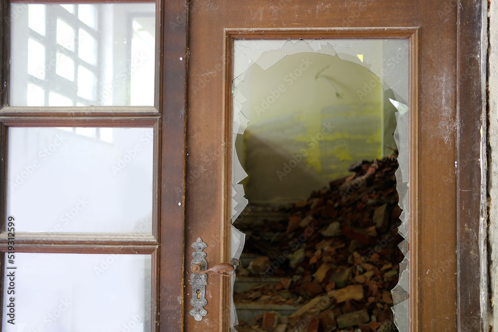 dirty broken door frame with hole in center, sharp pieces of glass ...