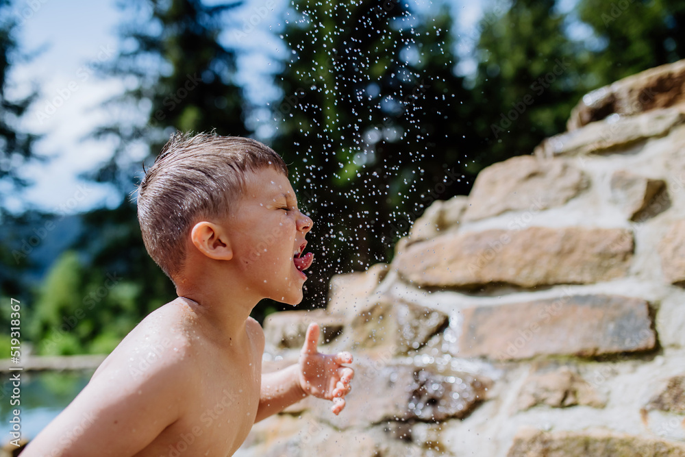 Funnz little boy coming out from garden pond with splashing around him ...