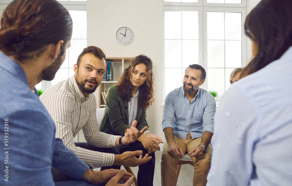 Different men and women at support group meeting listen to young man ...