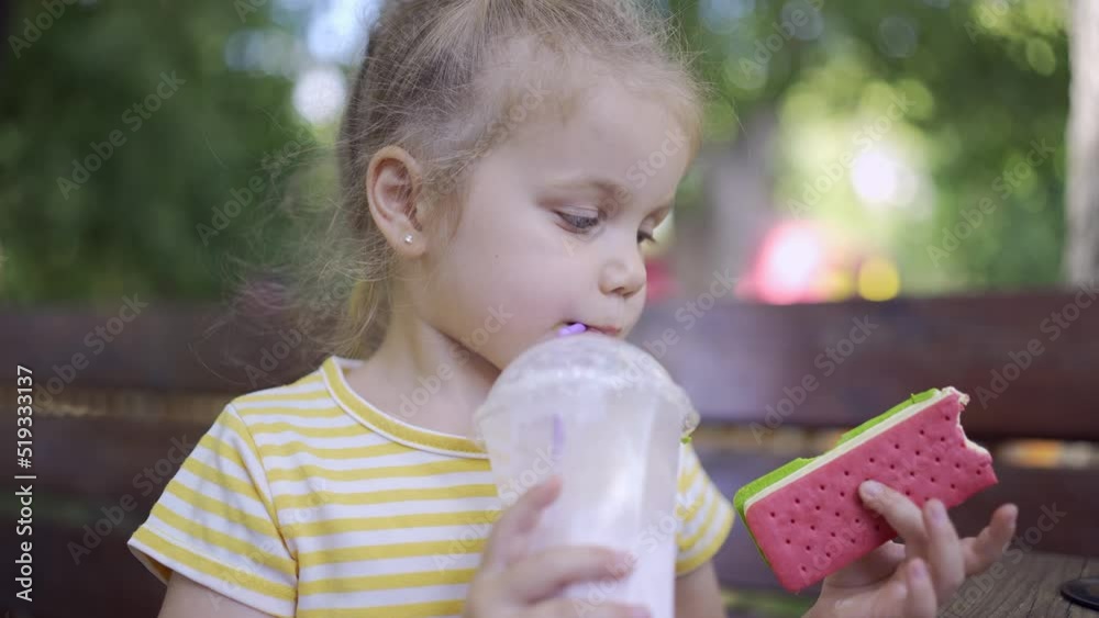 Little girl drinks a milkshake through a straw and smirks at ice cream ...