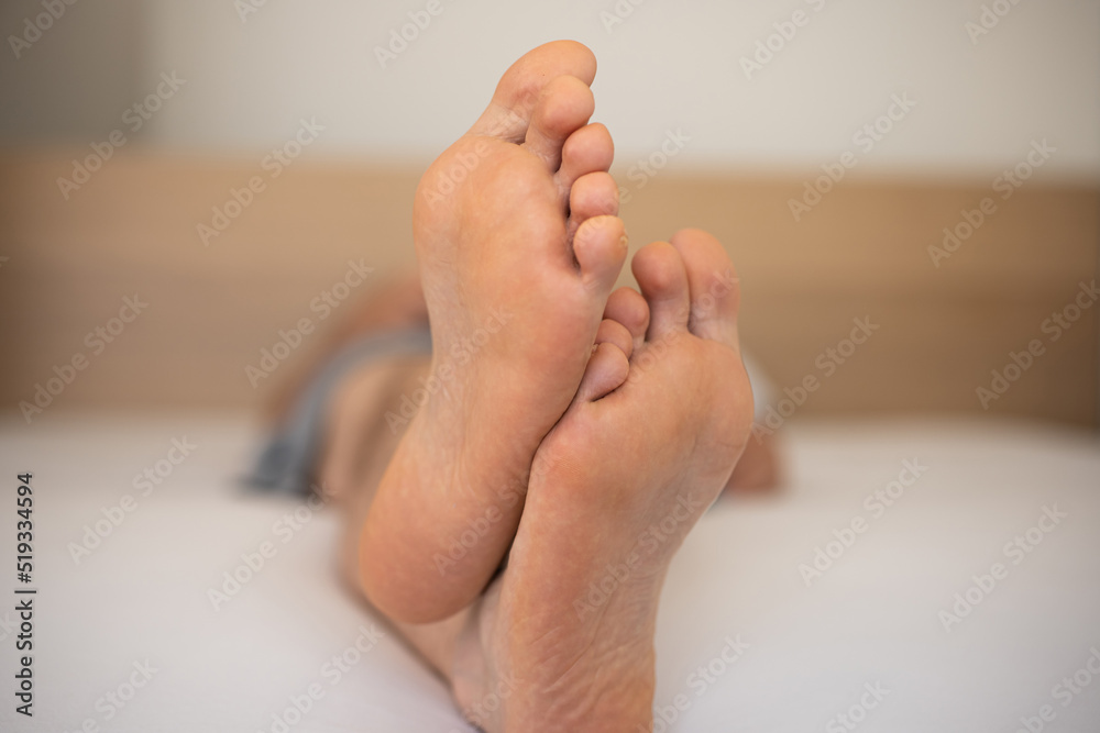 Caucasian man's bare feet laying on a bed, shallow depth of field ...