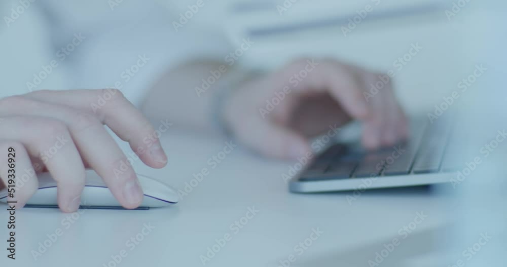 Young man working in a neutral tone office with computer using mouse ...