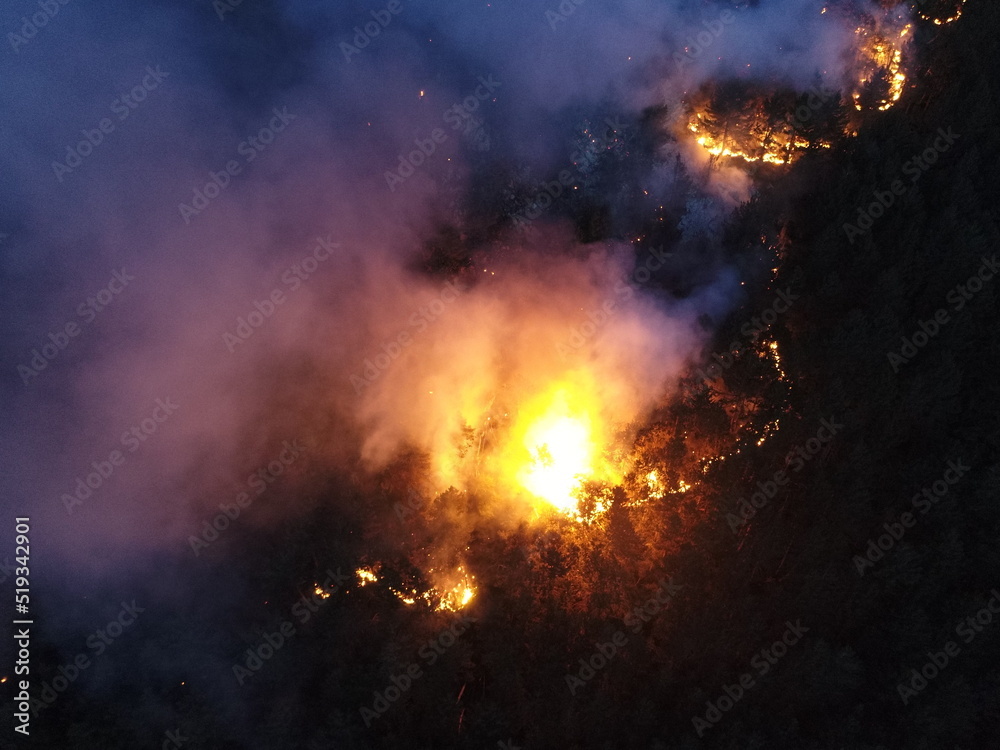 Aerial panoramic view of a forest fire at night, heavy smoke causes air ...