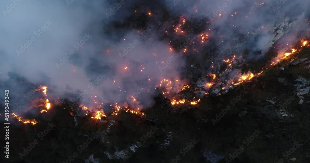 Aerial panoramic view of a forest fire at night, heavy smoke causes air ...