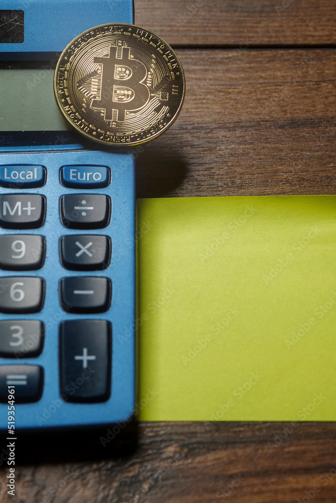 Bitcoin on a wooed surface and blue color calculator and empty memo ...