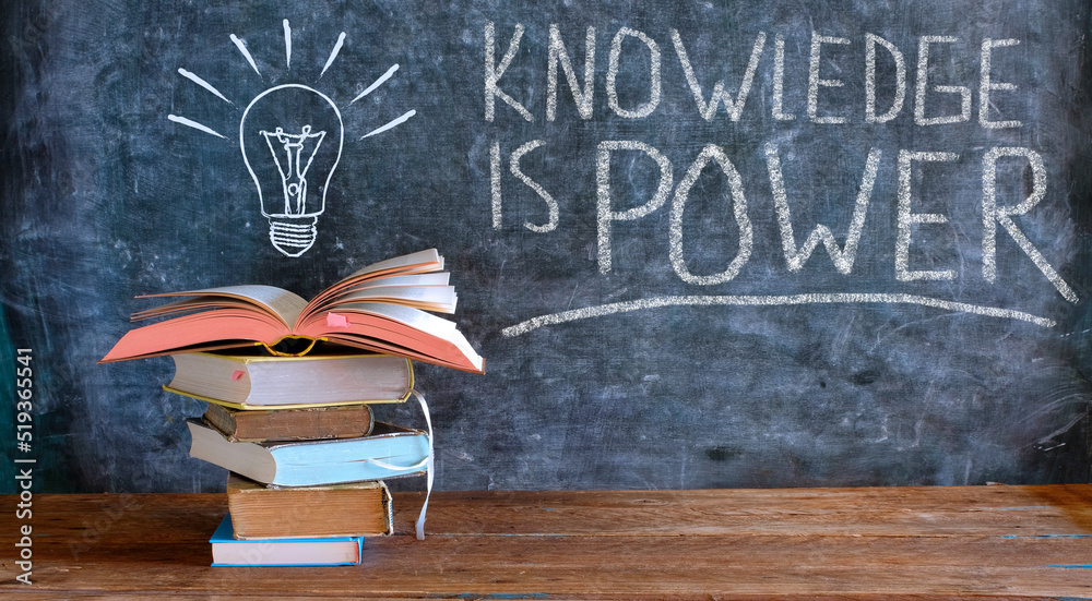 Foto de knowledge is power, books and blackboard with drawing of a ...