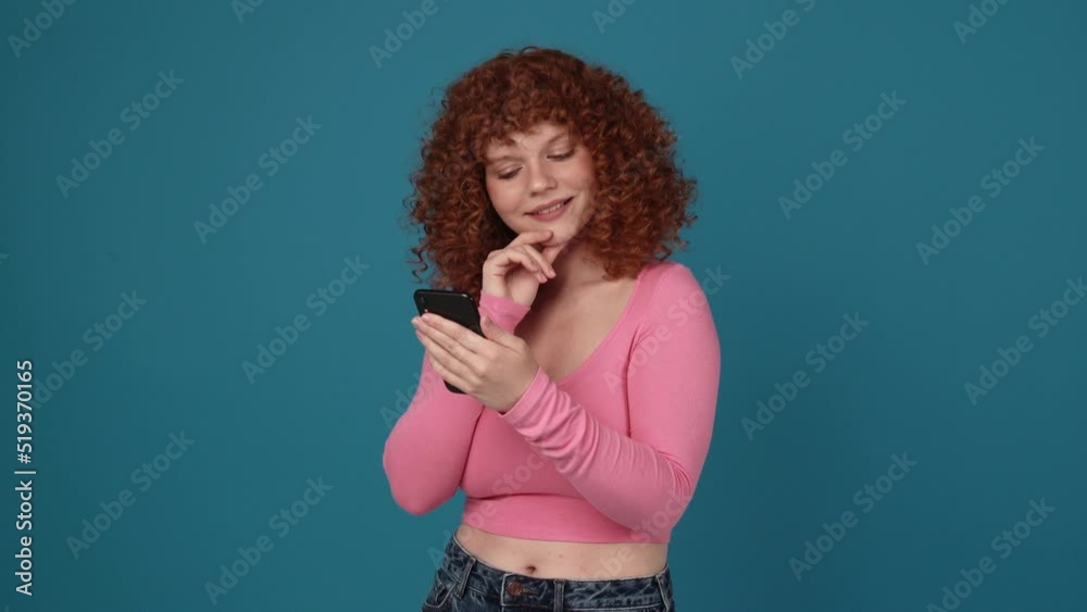 Pensive Curly Haired Redhead Woman Wearing Pink Shirt Texting On Phone