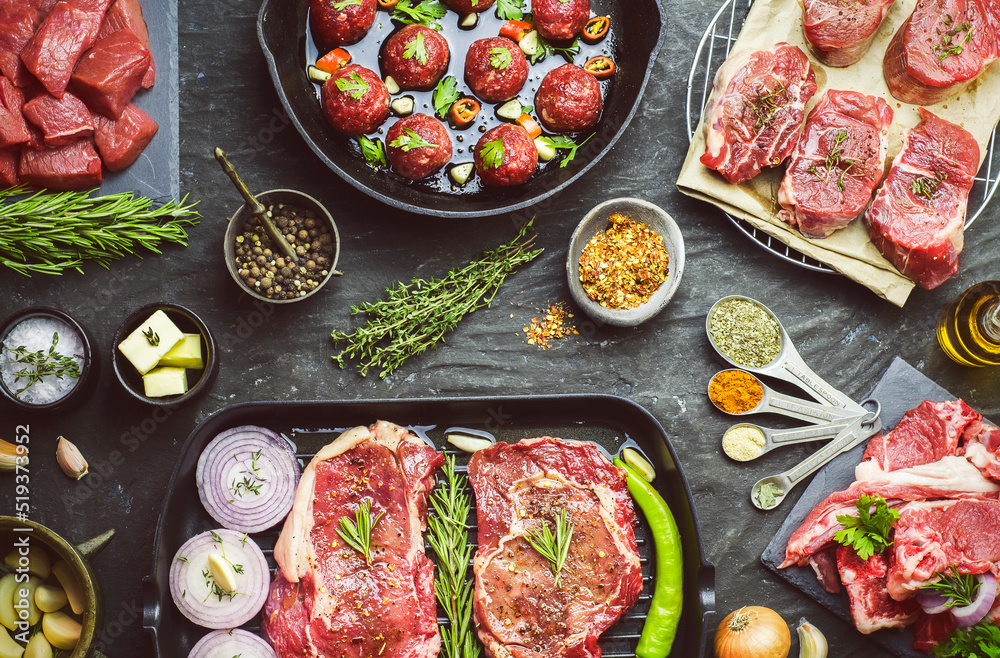 Different types of fresh raw meat sprinkled with seasonings and placed ...