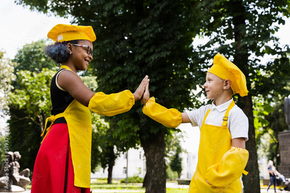 Black african and caucasian cook child in yellow chefs hat and apron ...