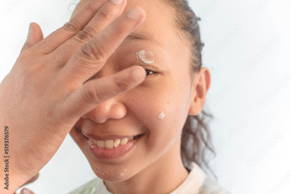 A makeup artist applies primer on a smiling young asian woman's face ...