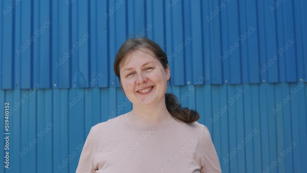 Portrait of simple young positive woman without makeup near blue ribbed ...